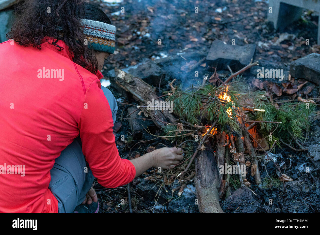 Woman starting a bonfire at a fireplace in the forest in autumn Stock ...