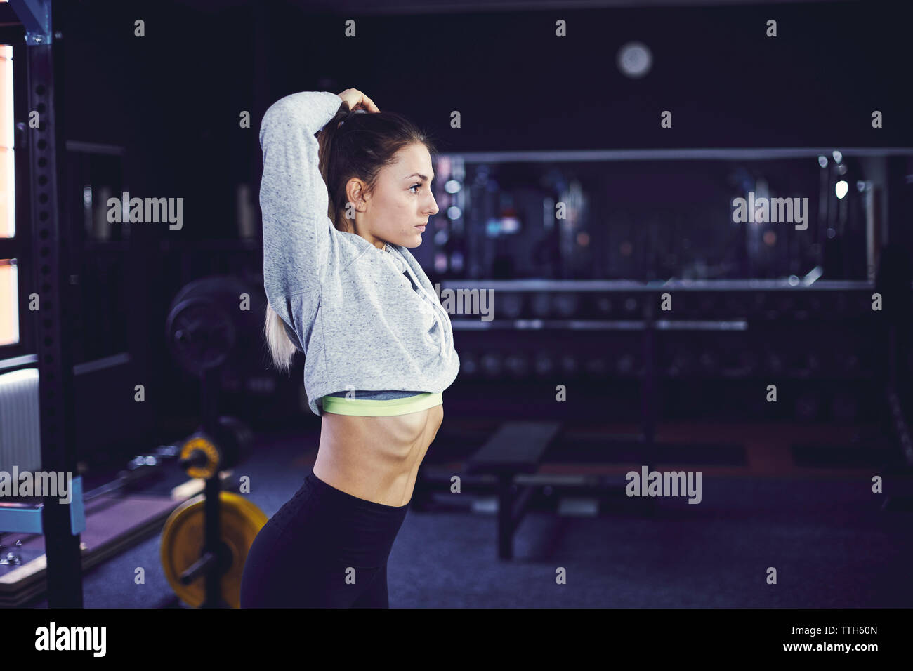 Side profile of young woman stretching at the fitness centre Stock ...