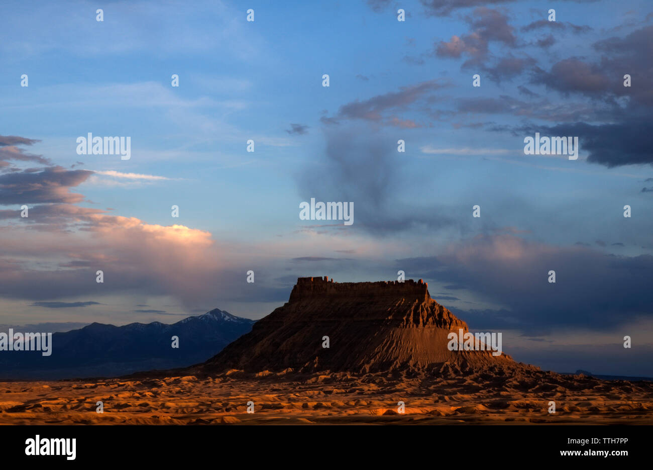 Sunset turns blue hills golden at the foot of Factory Butte Stock Photo ...