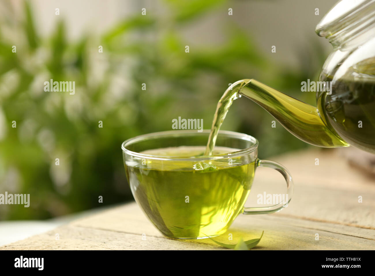 Teapot pouring tea in cup Stock Photo - Alamy