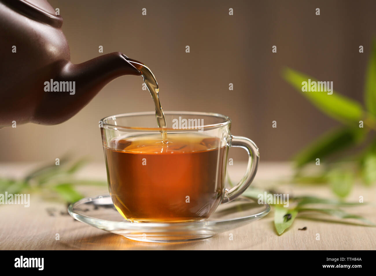 Teapot pouring tea in cup Stock Photo - Alamy