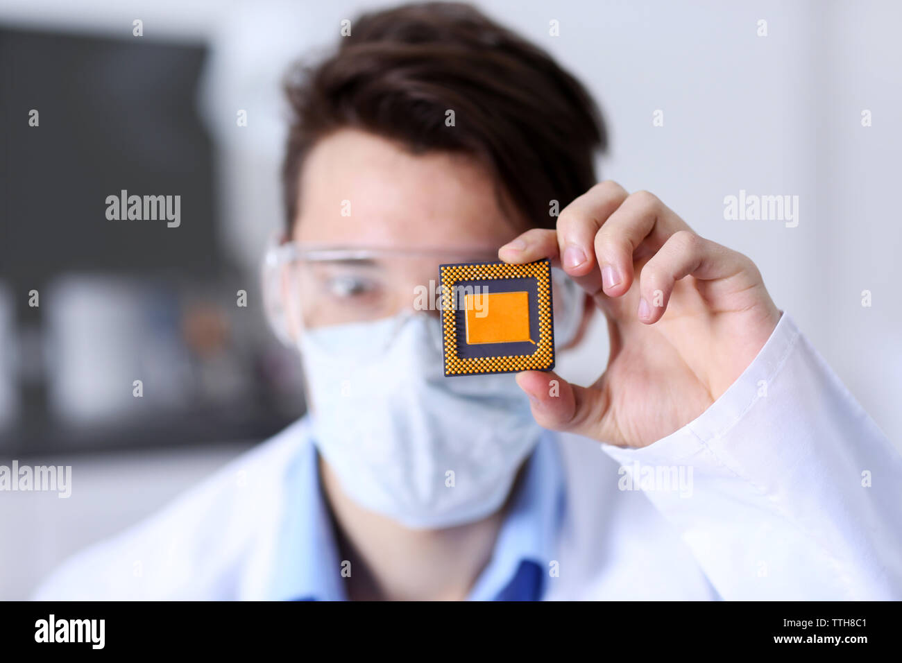 Young man in glasses and mask holding computer processor near eye Stock ...