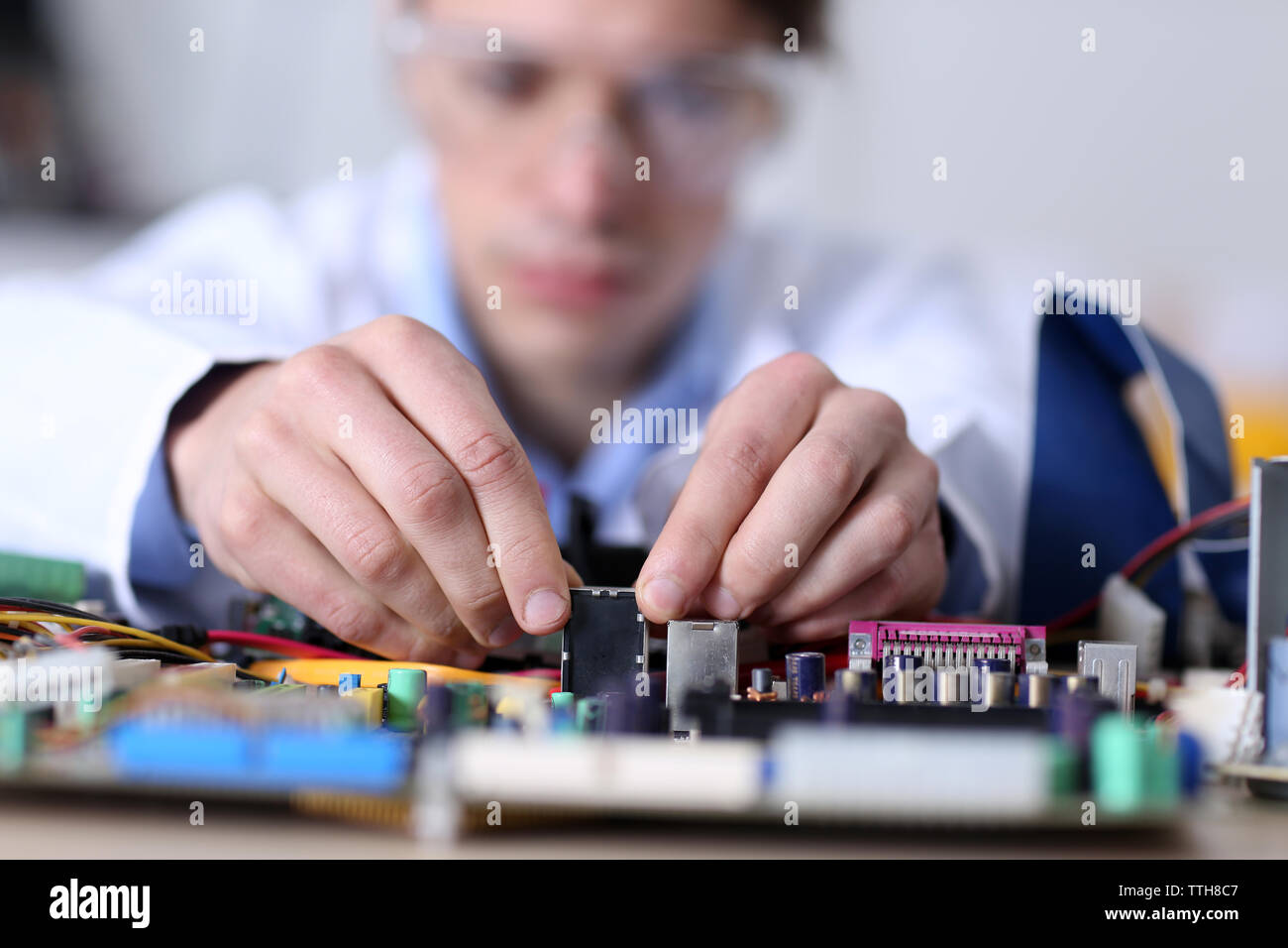 Young man in glasses repairing computer hardware in service center ...