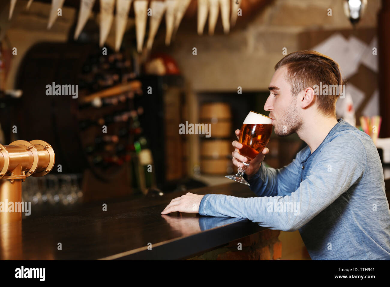 Young man drinking beer in a bar Stock Photo - Alamy