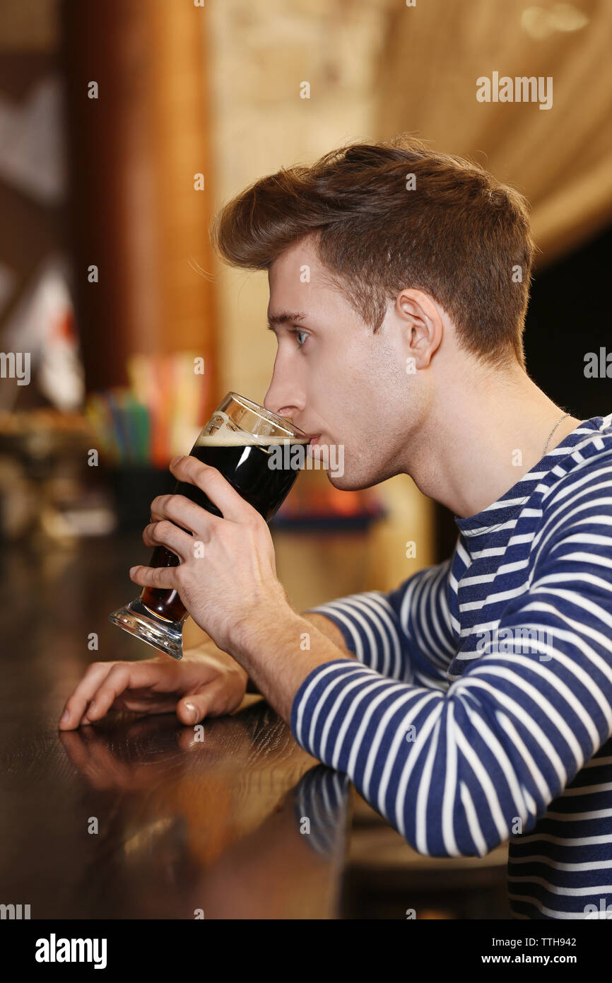 Young man drinking beer in a bar Stock Photo - Alamy