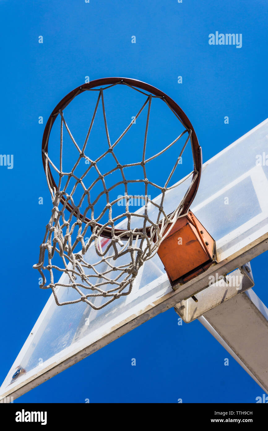 Basketball backboard, ring and net against blue sky when looking upward ...