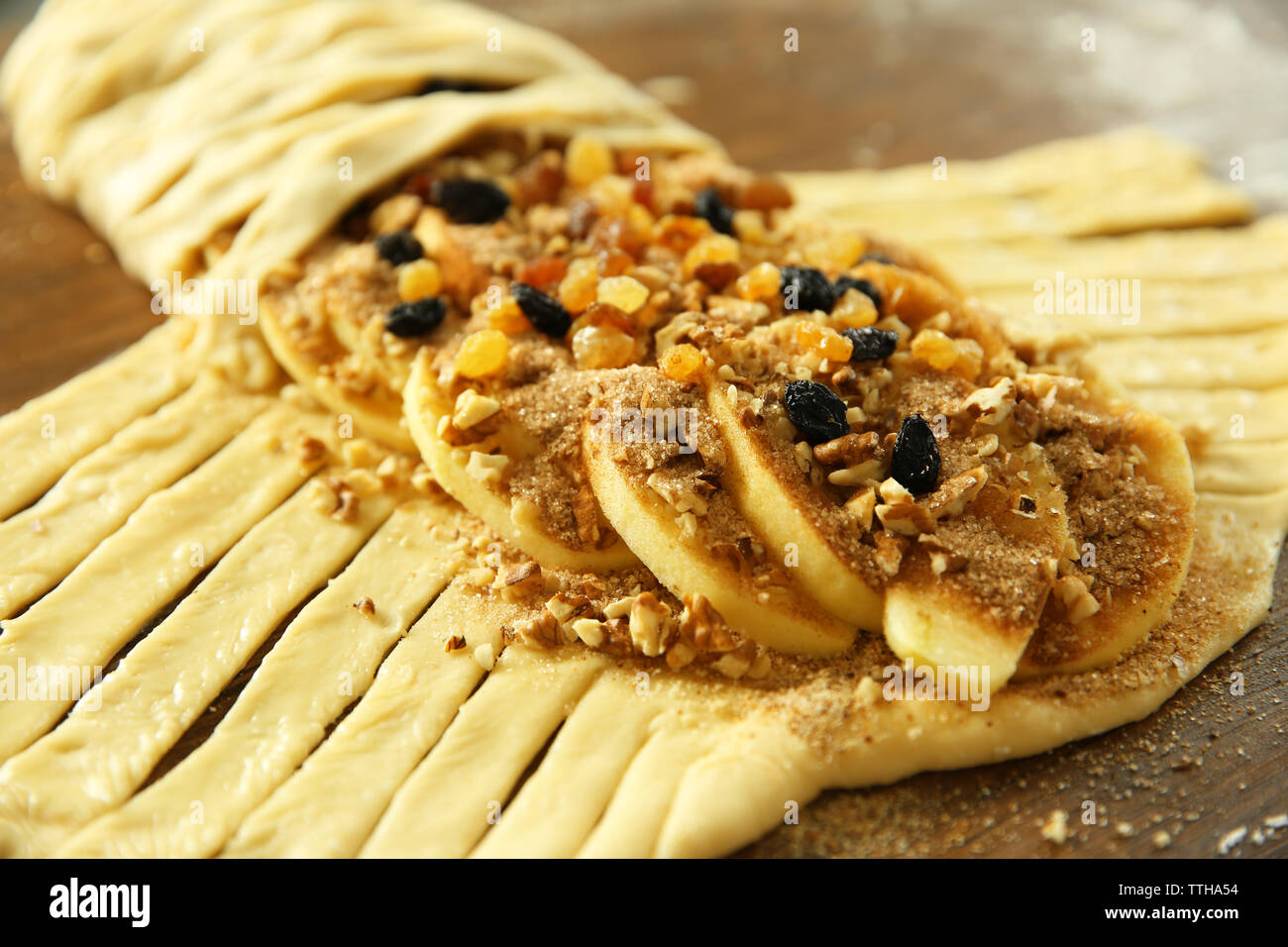 Strudel with apples, walnut and raisins in raw dough on wooden table ...