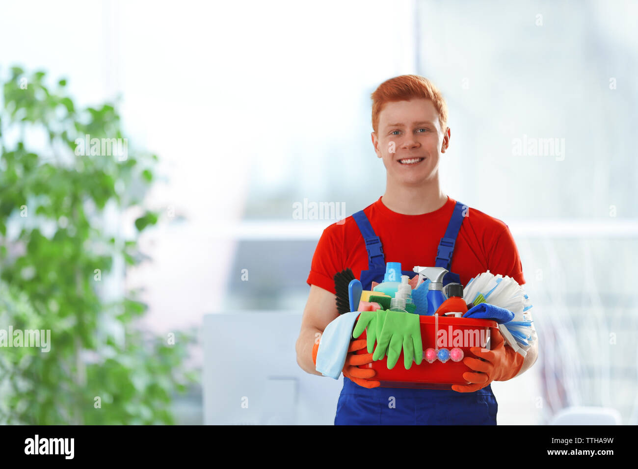 Young janitor holding cleaning products and tools on tub Stock Photo ...