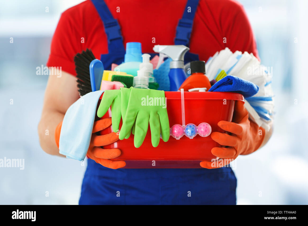Young janitor holding cleaning products and tools on tub, close up ...