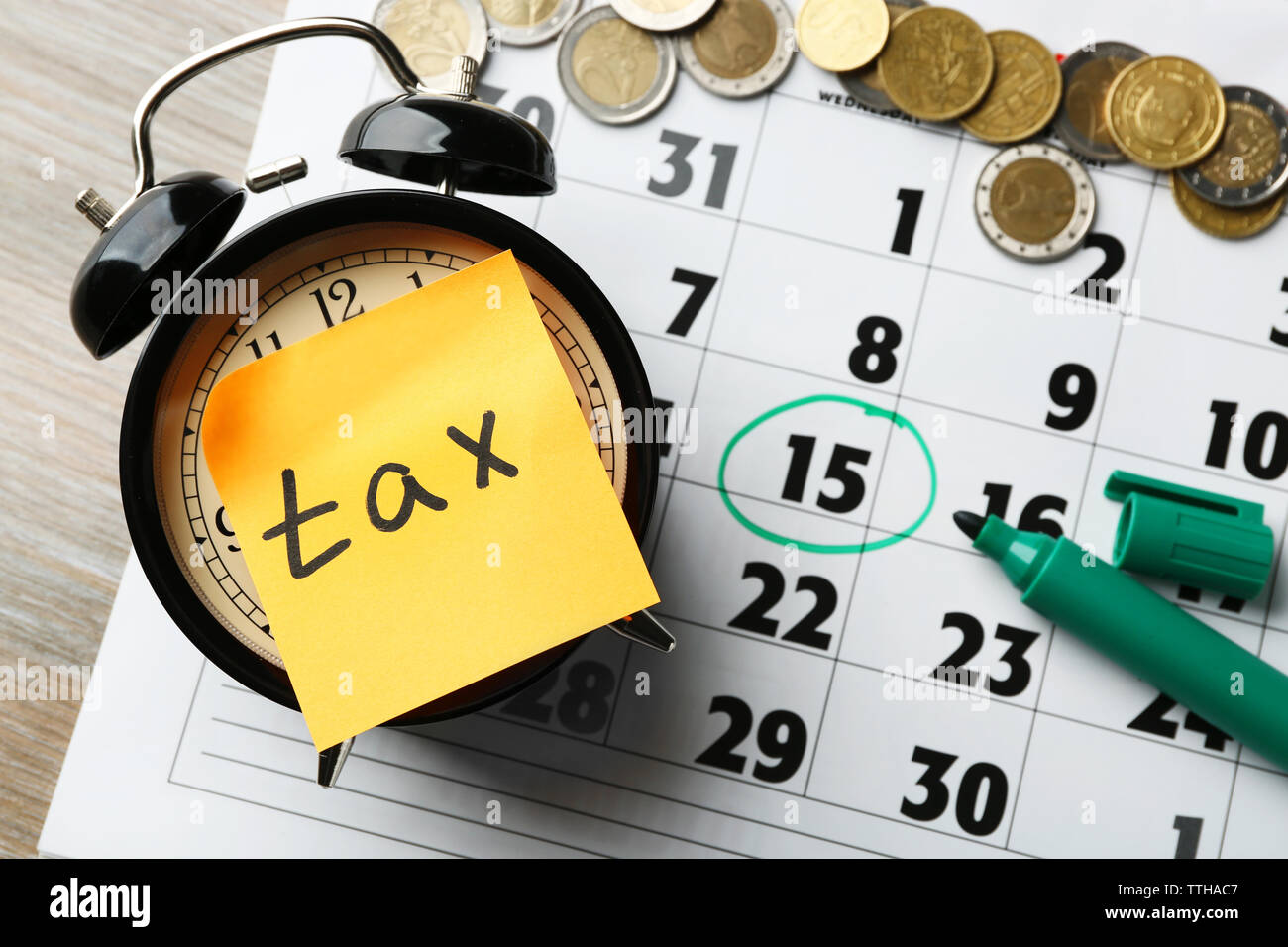 Tax time on alarm clock with coins, marker and calendar Stock Photo - Alamy