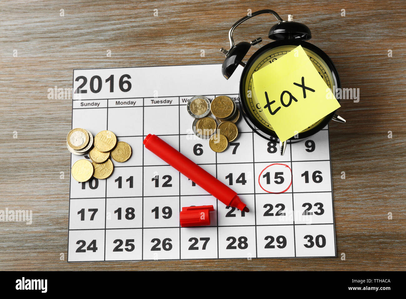 Tax time on alarm clock with coins, marker and calendar Stock Photo - Alamy
