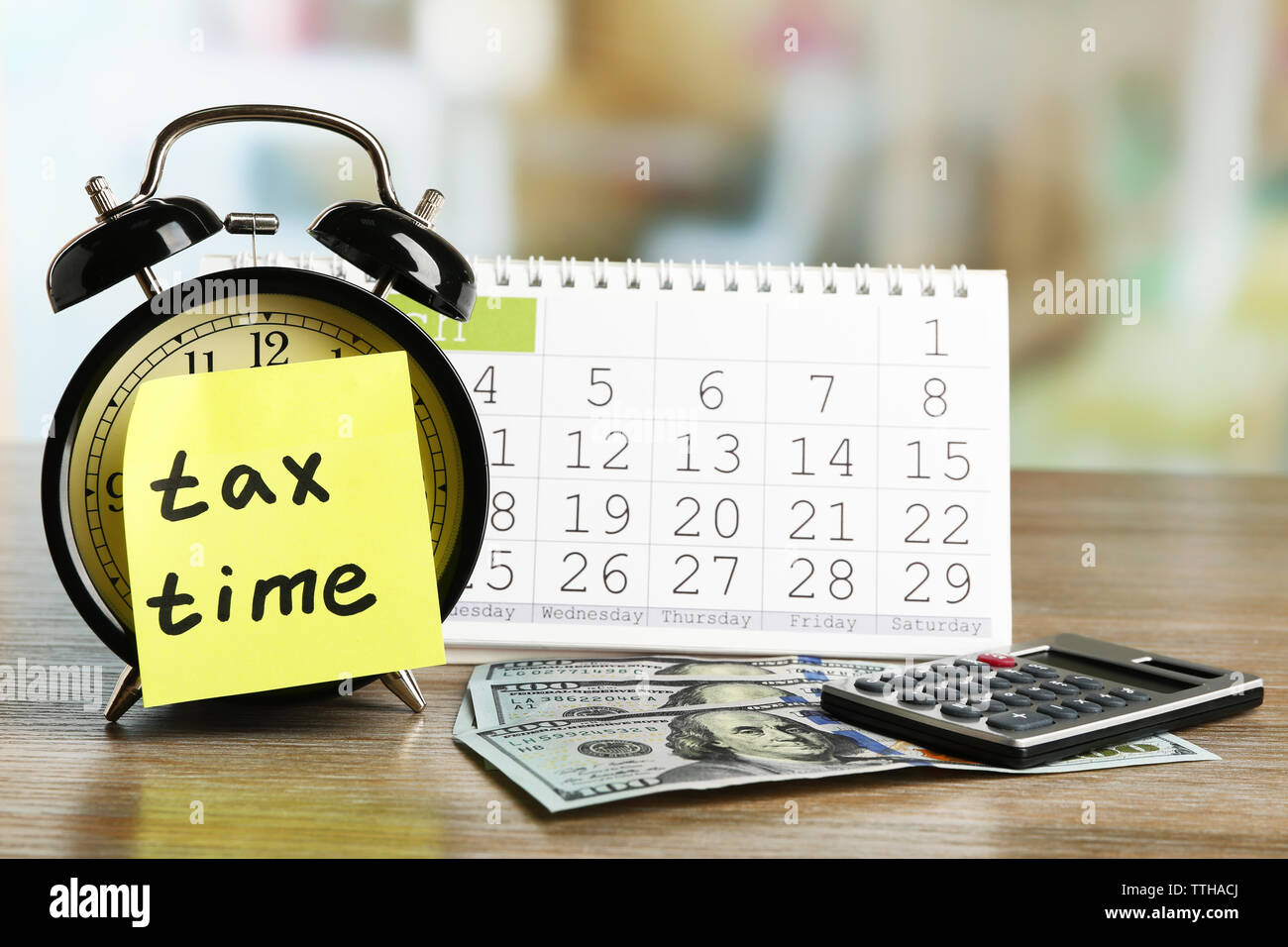 Tax time on alarm clock with dollars, calculator and calendar Stock ...