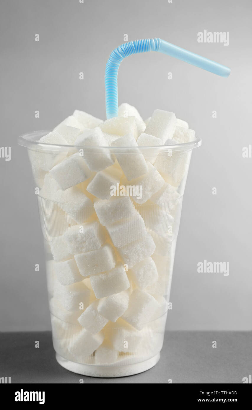 Plastic glass full of sugar with straw on grey background Stock Photo ...