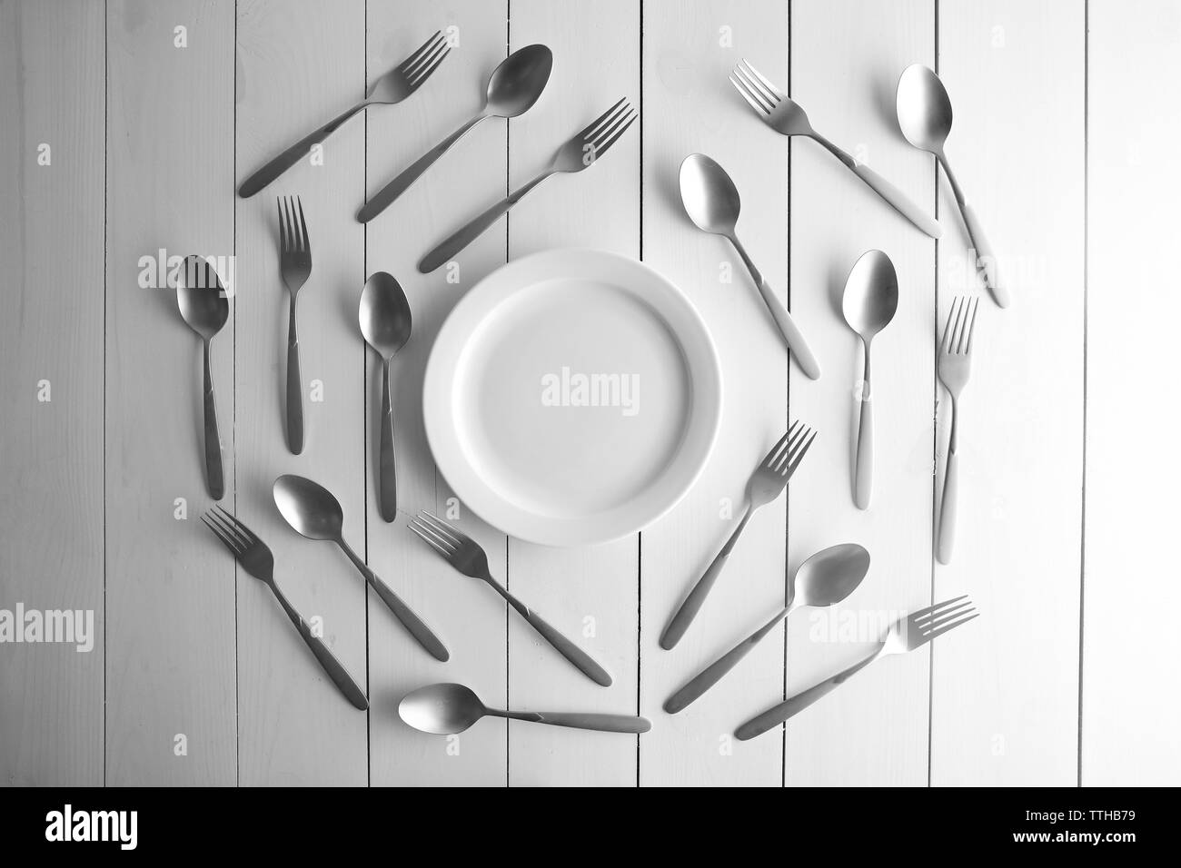 Plate and silver flatware on white table, top view Stock Photo - Alamy