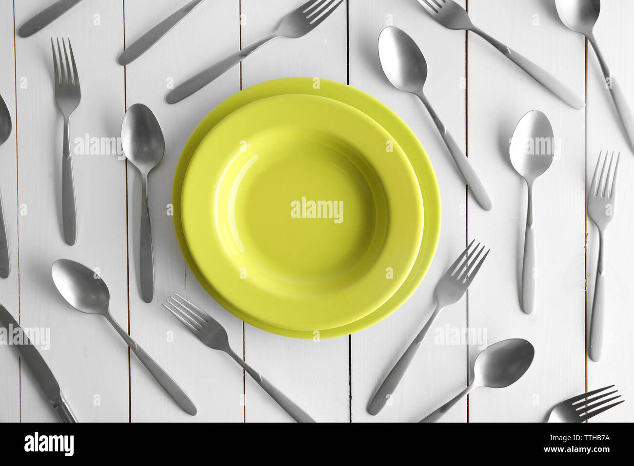Plate and silver flatware on white table, top view Stock Photo - Alamy