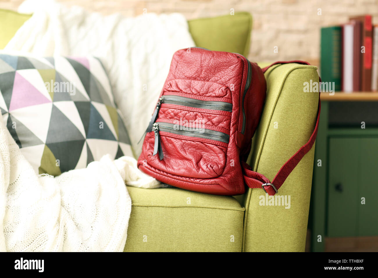 Red leather backpack on the green couch Stock Photo - Alamy