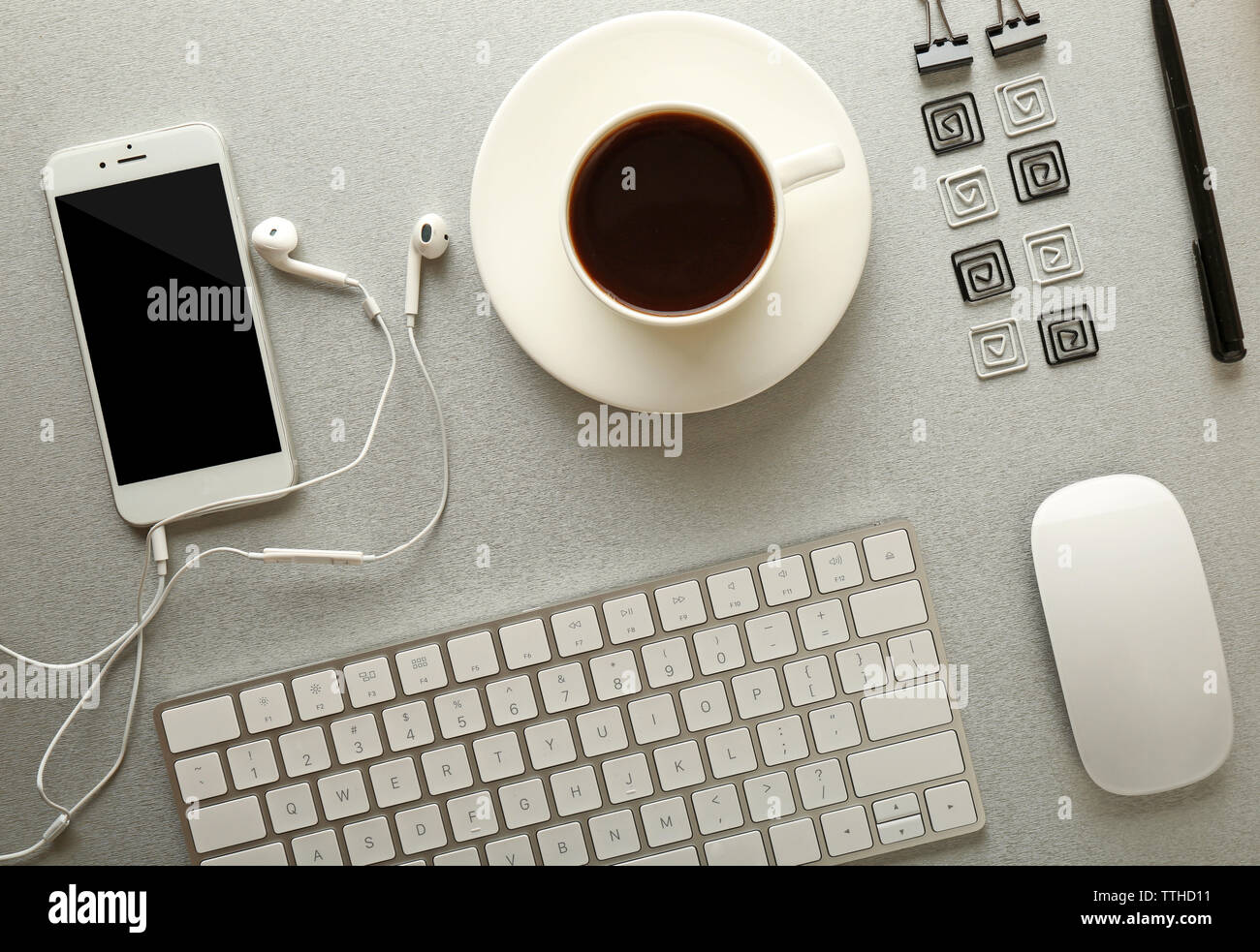 Workplace with mobile phone, peripheral devices and stationery on grey ...