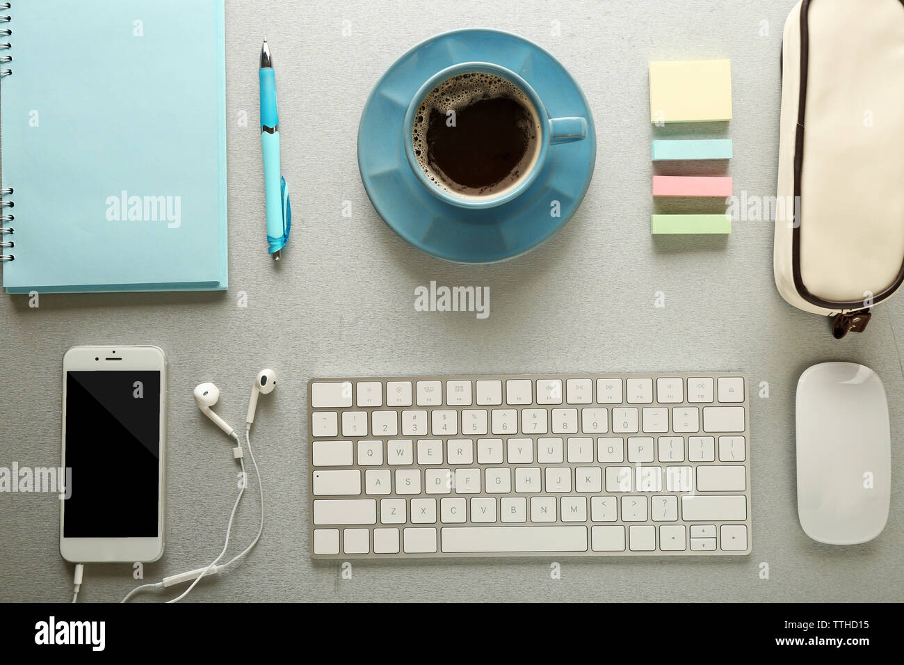 Workplace with mobile phone, peripheral devices and stationery on grey ...