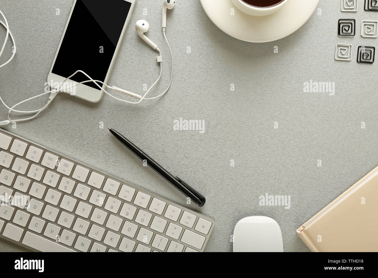 Workplace with mobile phone, peripheral devices and stationery on grey ...