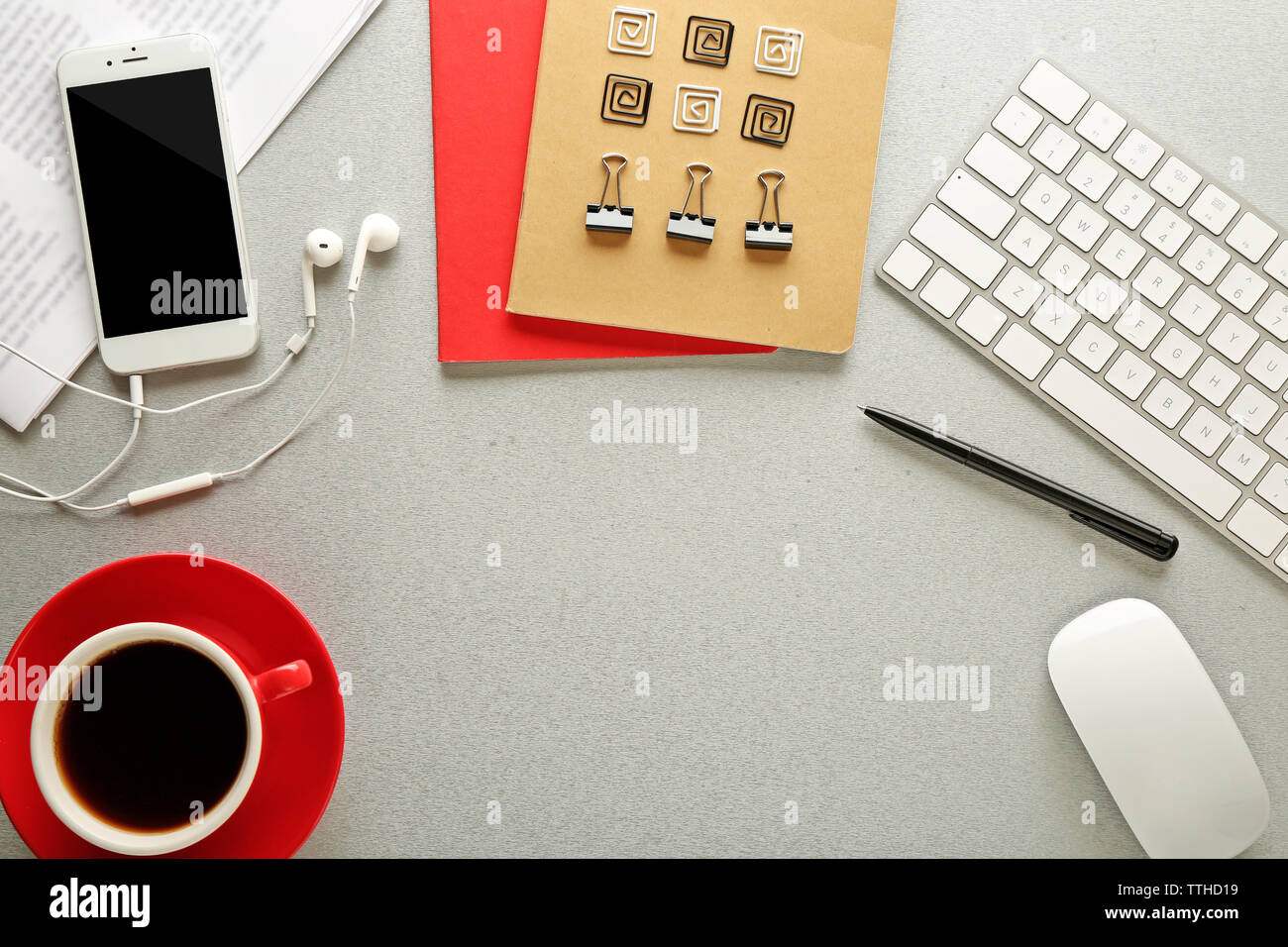 Workplace with mobile phone, peripheral devices and stationery on grey ...