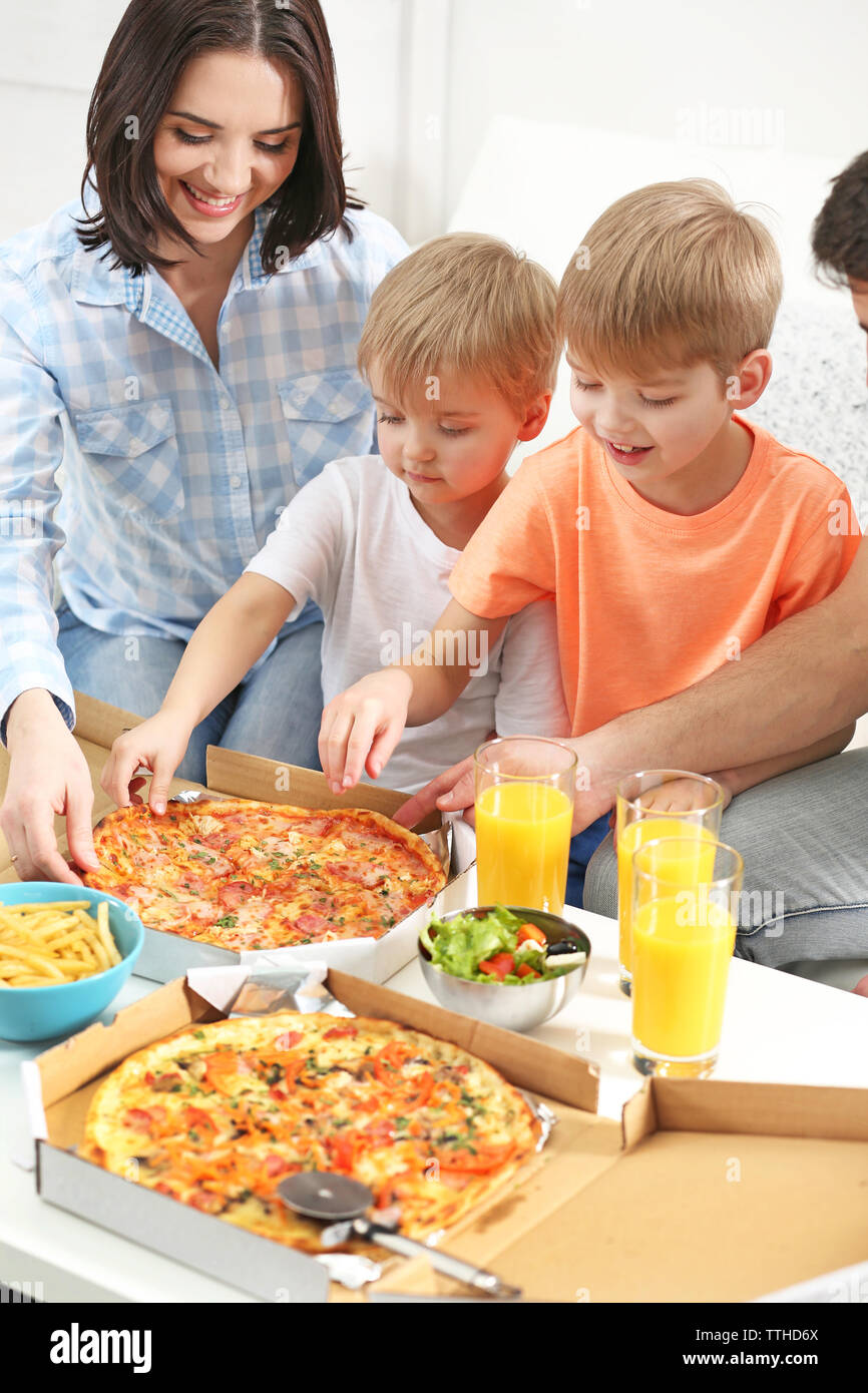 Happy family eating pizza on sofa all together Stock Photo - Alamy