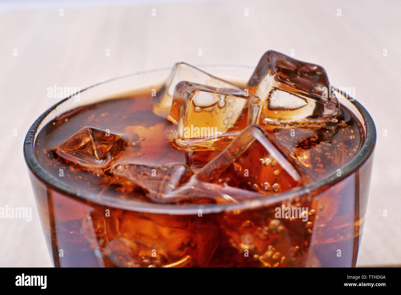 Glass of cola with ice on light wooden background Stock Photo - Alamy