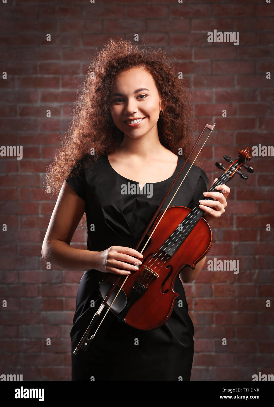 Beautiful young woman holding violin over brick wall background Stock ...