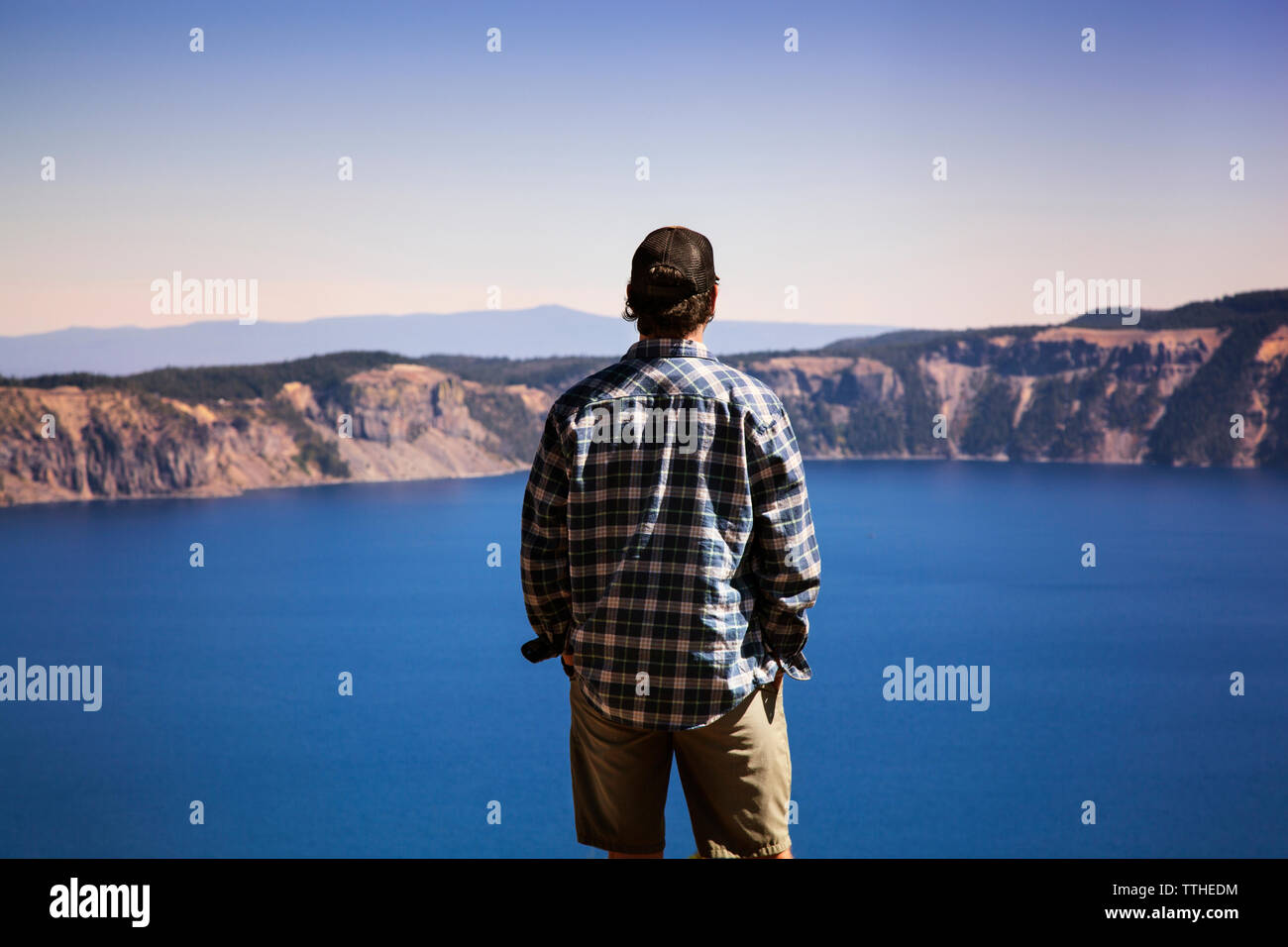 Rear view of man looking at lake against clear sky Stock Photo - Alamy