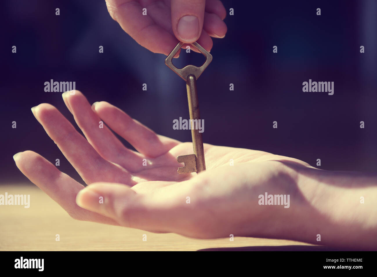 Female hand giving old key to other hand on blurred background Stock ...