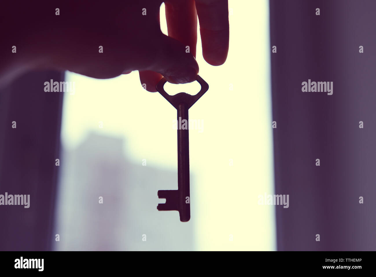 Female hand holding old key on blurred background Stock Photo - Alamy