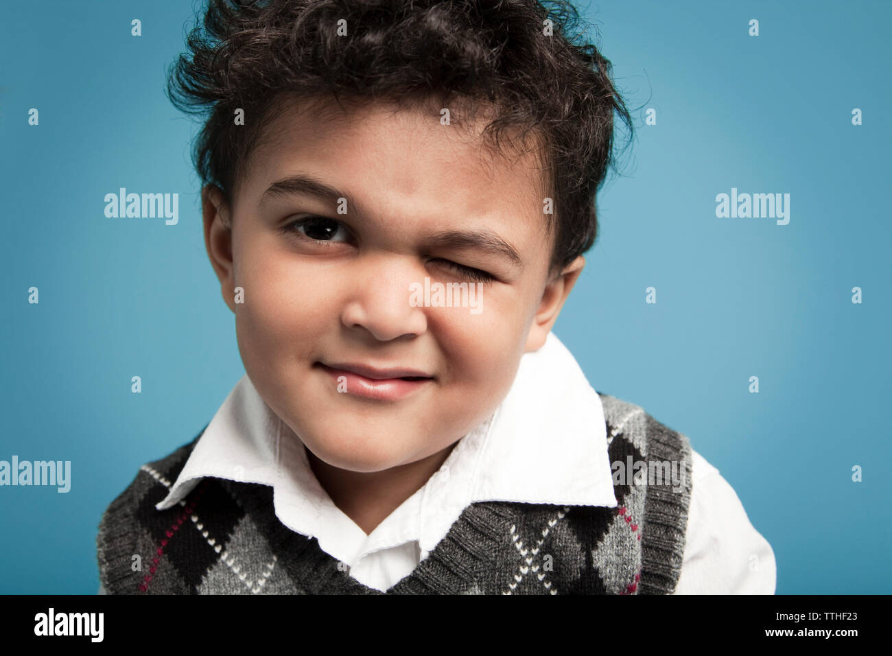 Portrait of winking boy against blue background Stock Photo - Alamy
