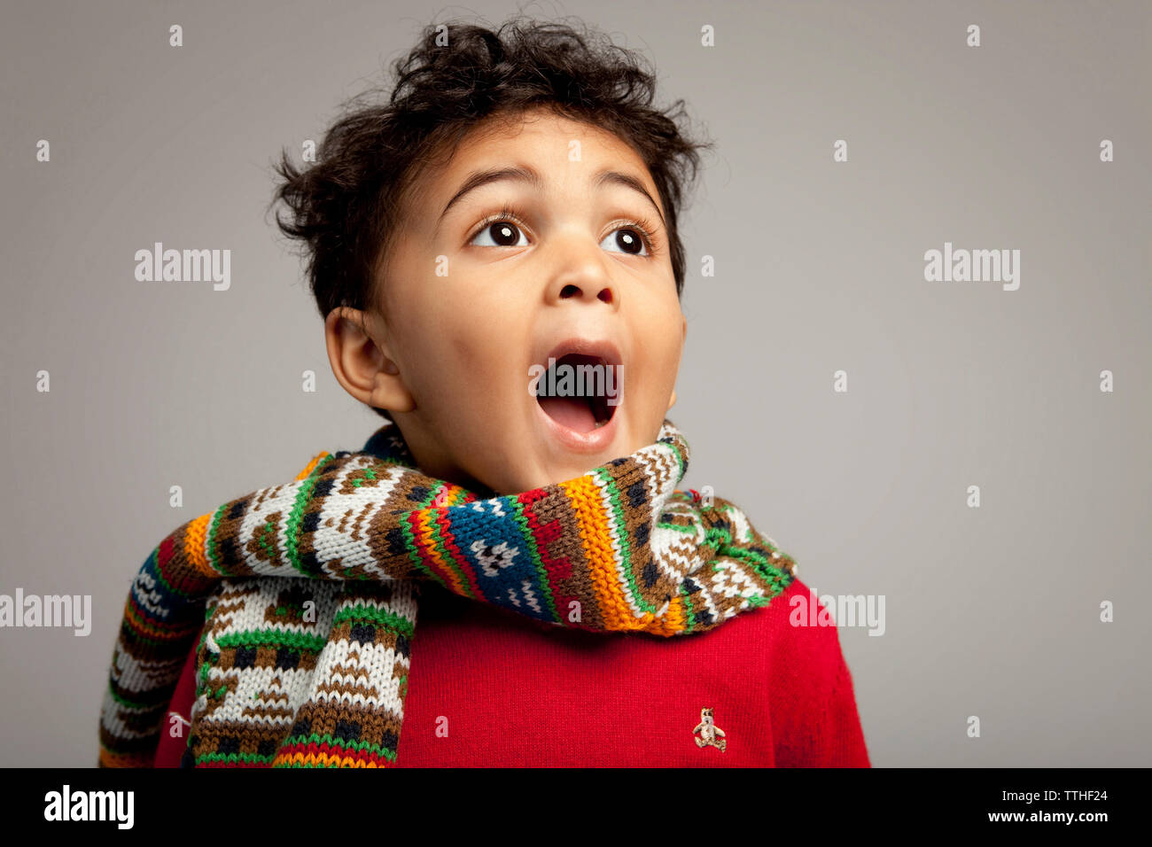 Close-up of surprised boy looking away against gray background Stock ...