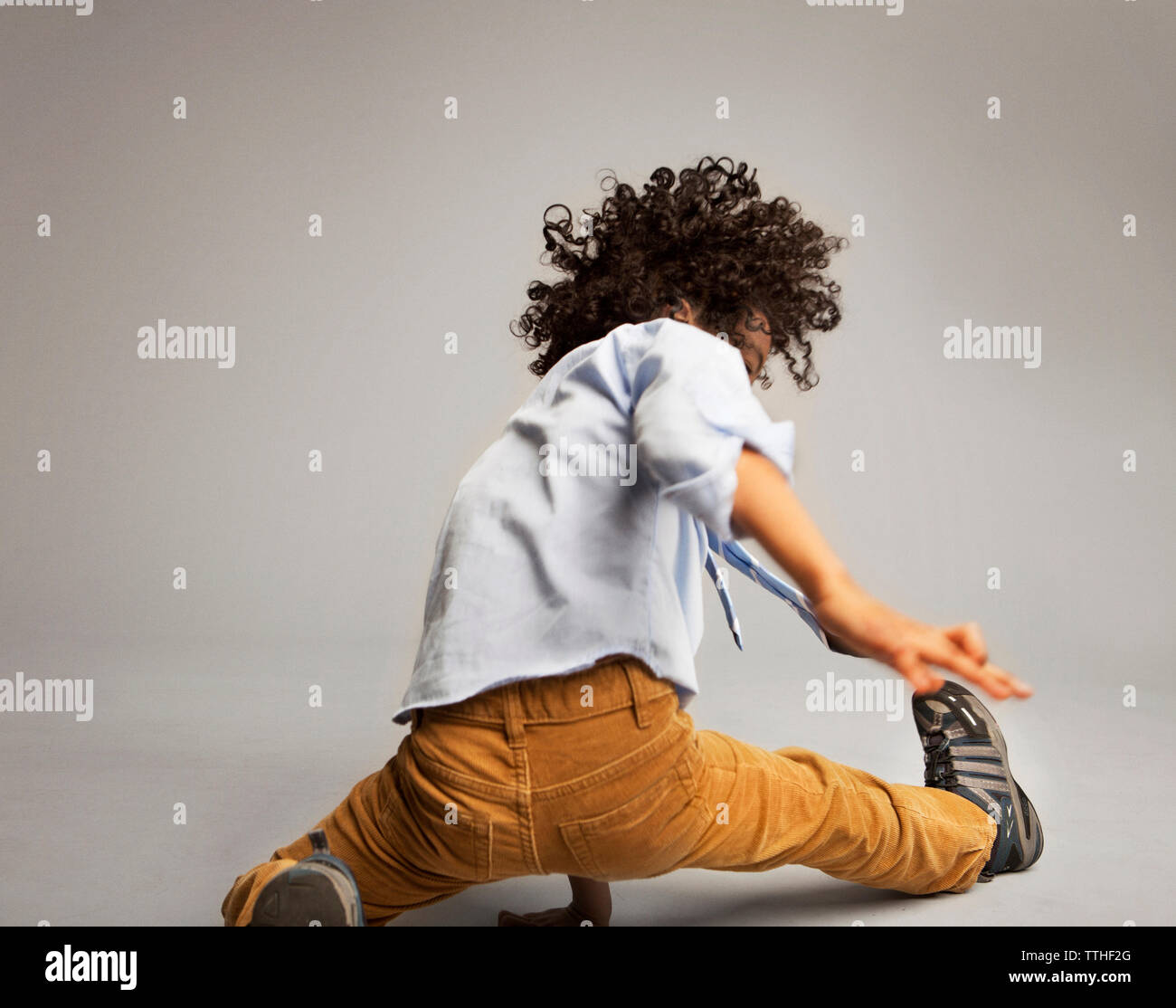Rear view of boy doing splits against gray background Stock Photo - Alamy