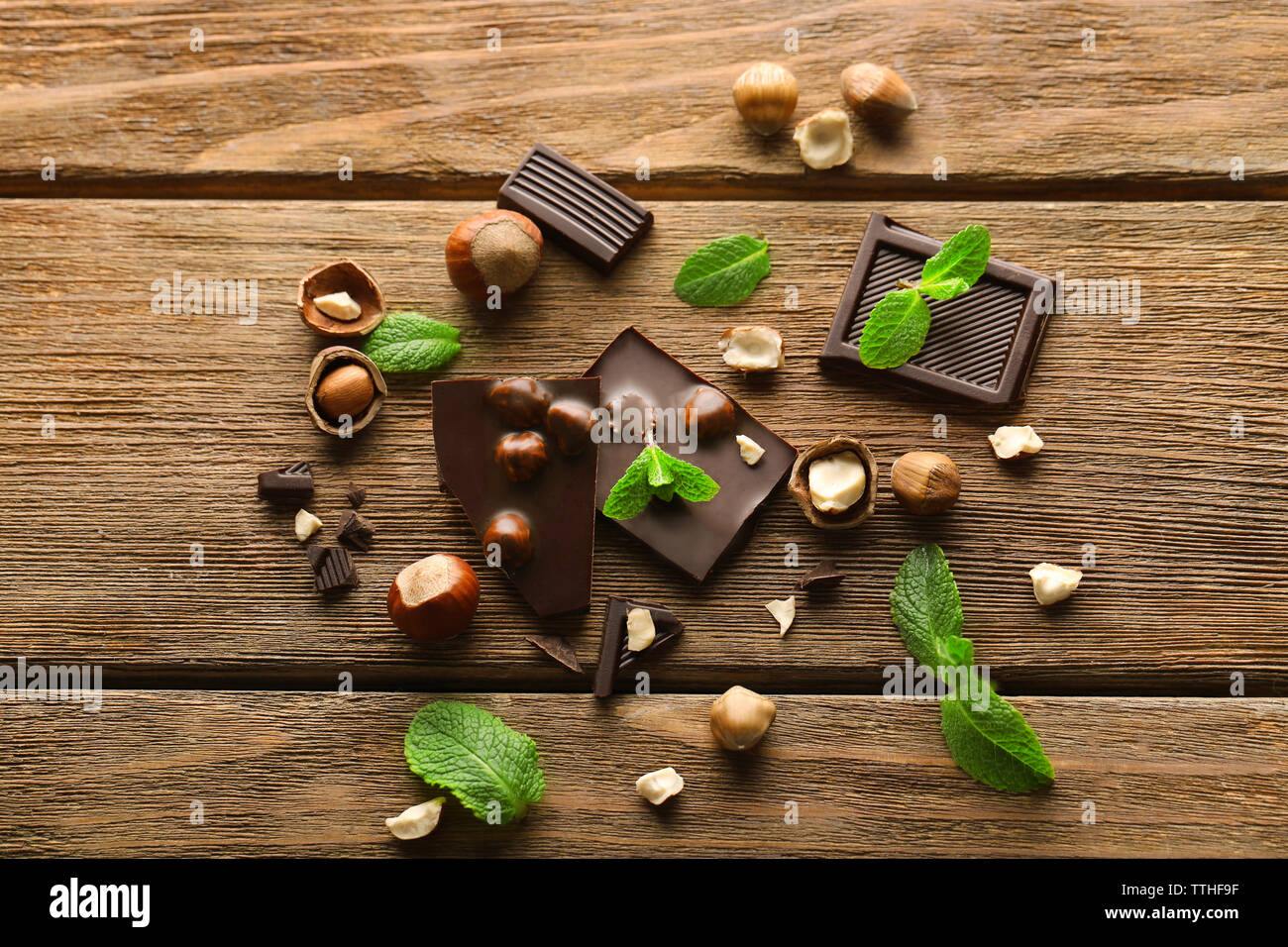Chopped chocolate bar with mint and hazelnuts on wooden table Stock ...
