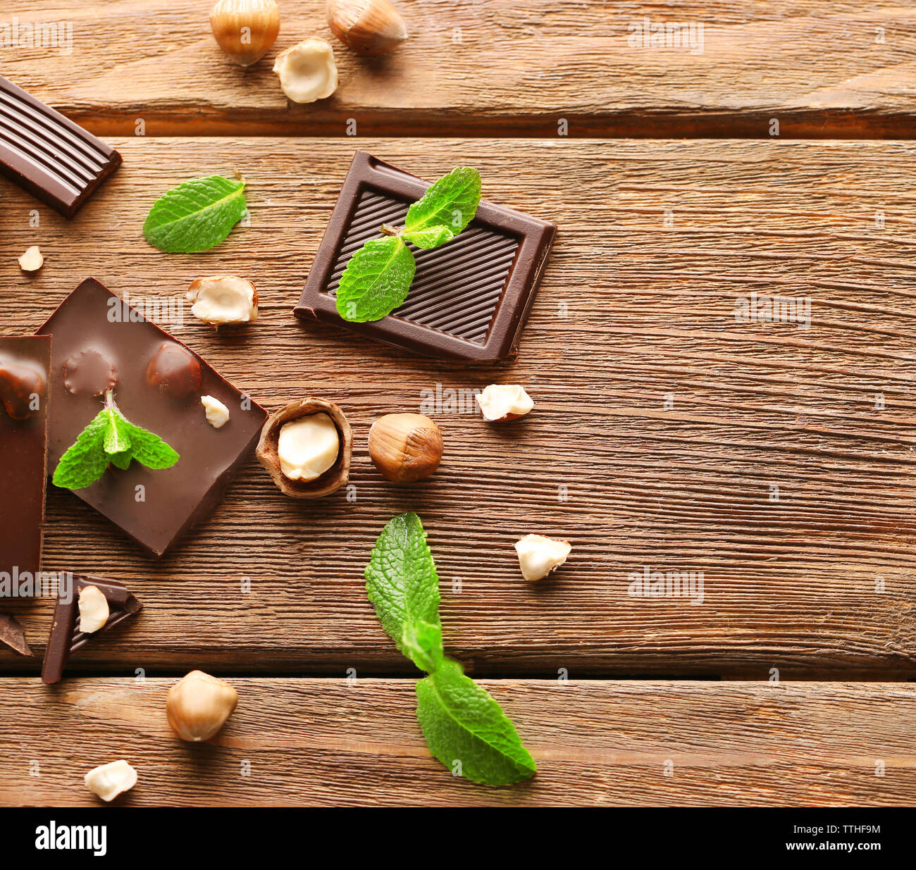 Chopped chocolate bar with mint and hazelnuts on wooden table Stock ...