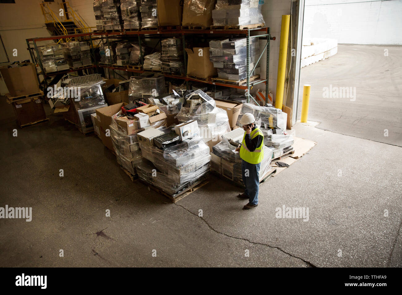 Male worker talking on mobile phone while standing by E-Waste in ...