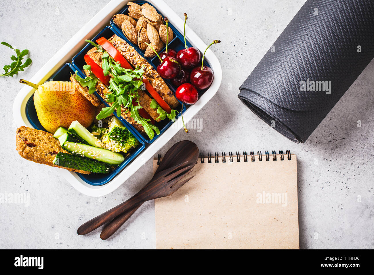 Lunch box with sandwich, pear, vegetables, nuts and snacks on a gray ...