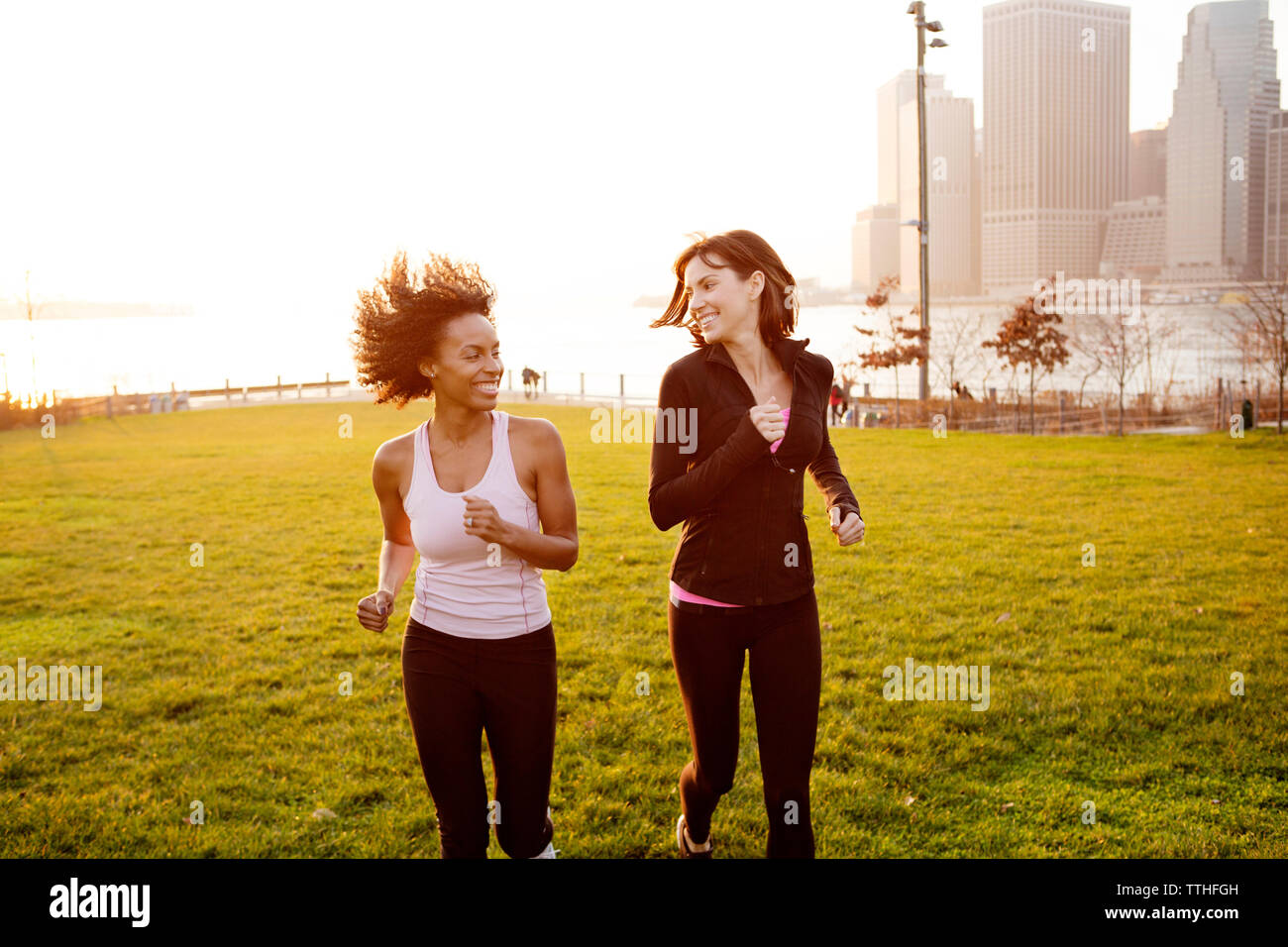 Happy female friends jogging at park in city Stock Photo - Alamy