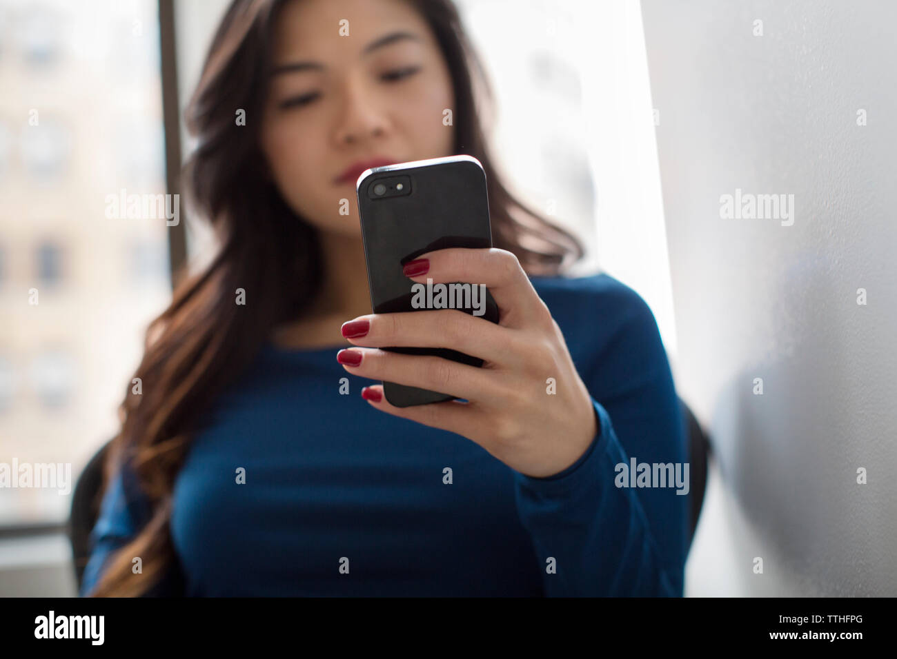 Woman text messaging while sitting at office Stock Photo - Alamy