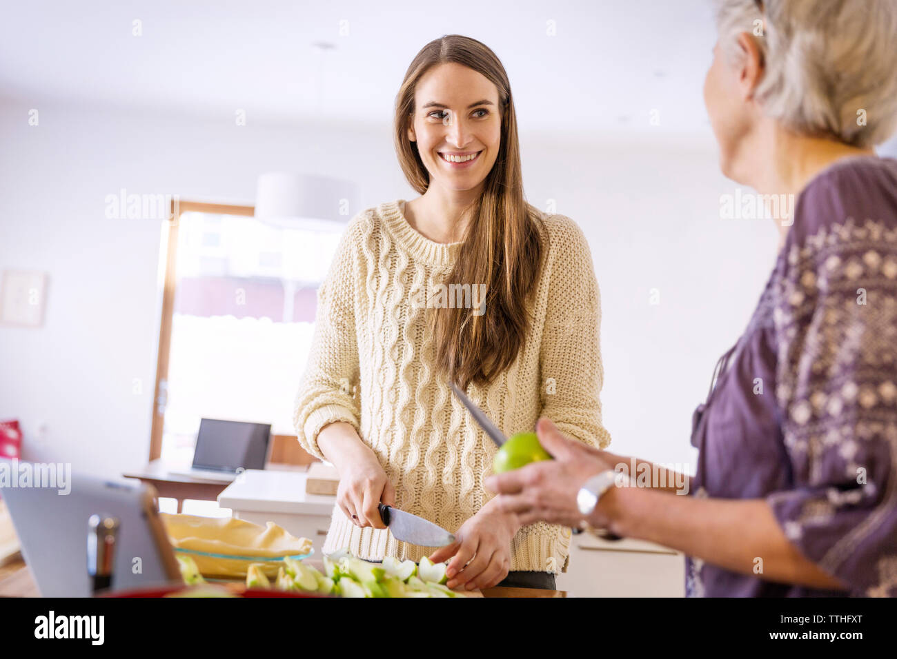 Daughter looking at mother while working in kitchen Stock Photo - Alamy