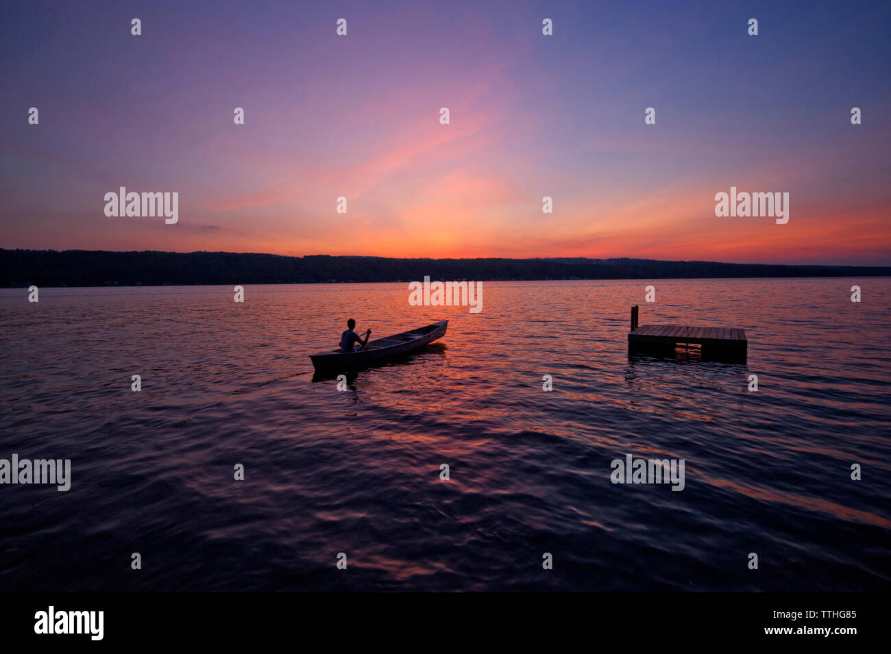 Man oaring boat on lake against sky during sunset Stock Photo - Alamy