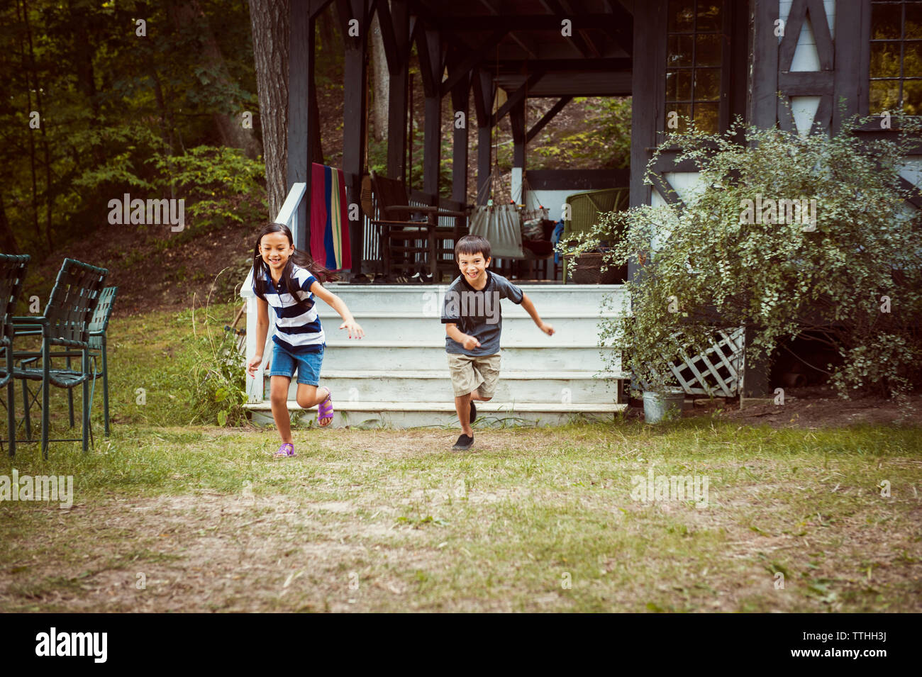 Happy siblings running on field in front yard Stock Photo - Alamy