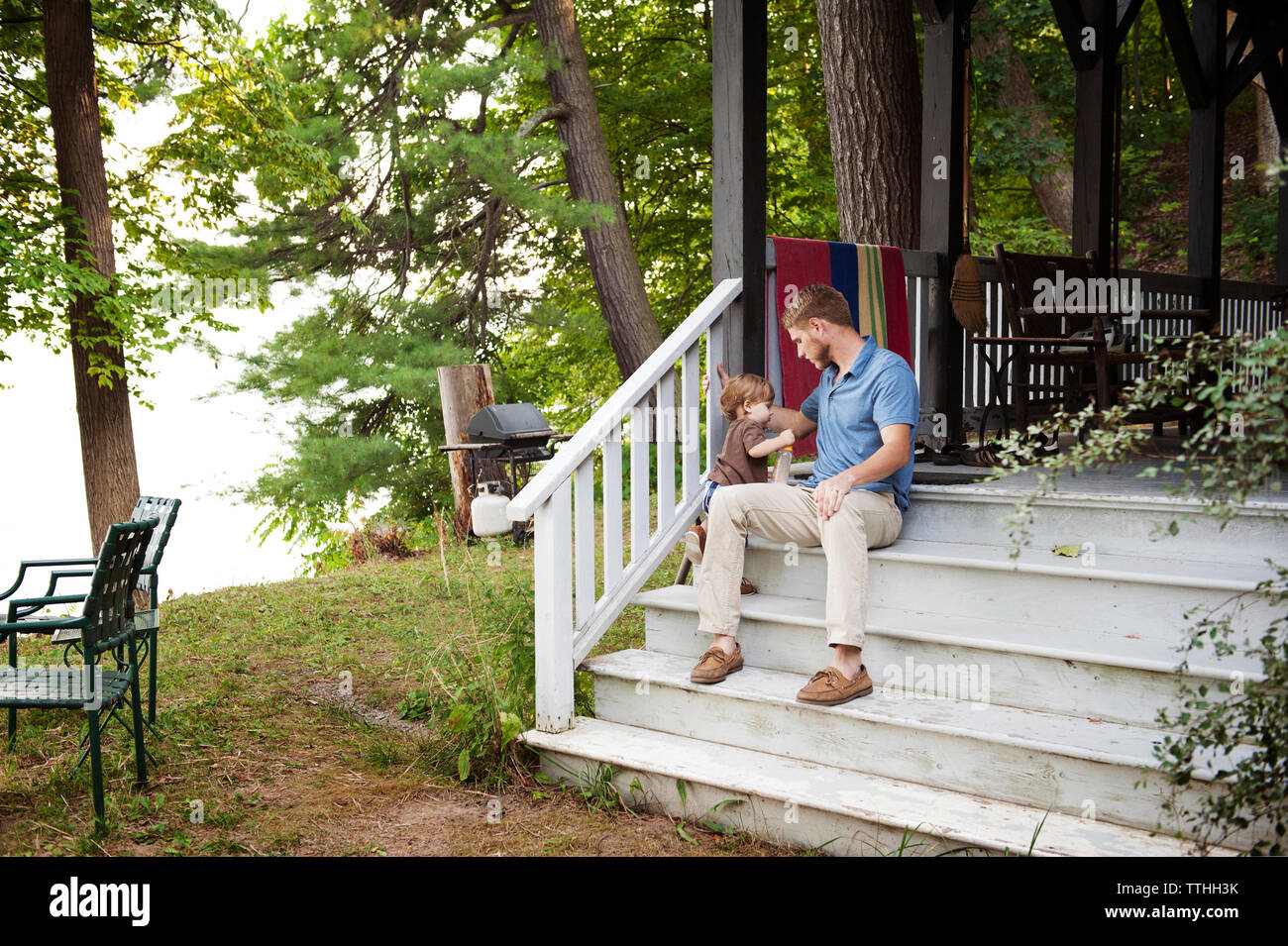 Father and son on steps at porch against trees Stock Photo - Alamy