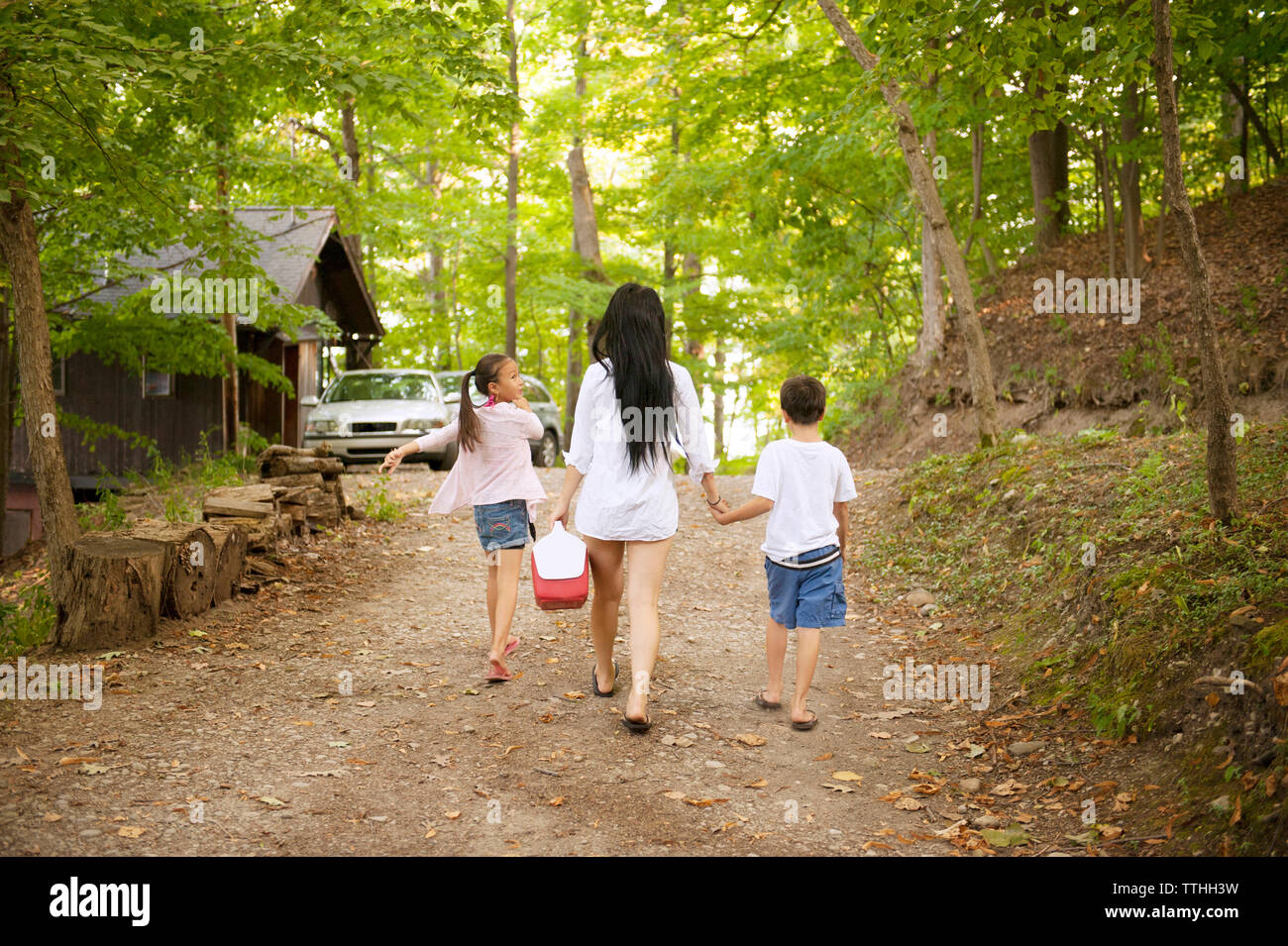 Rear view of mother walking with children on dirt road in forest Stock ...