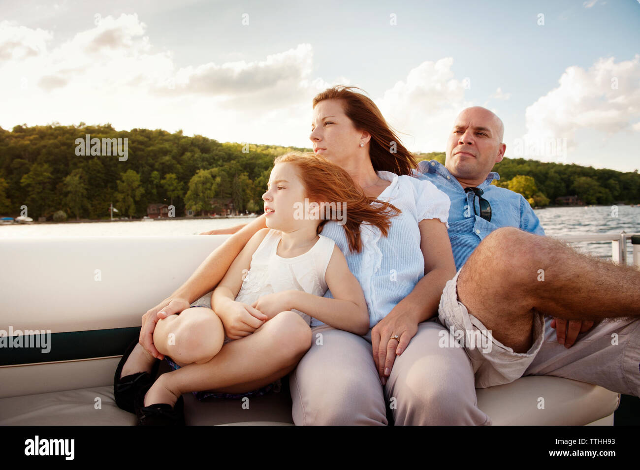 Girl relaxing with parents while traveling in boat on lake Stock Photo ...