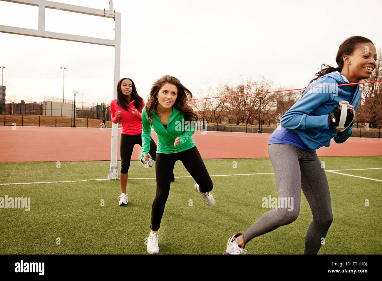 Female athletes exercising on playing field against clear sky Stock ...