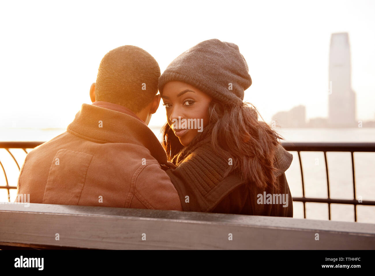 Portrait of woman sitting with boyfriend on bench Stock Photo - Alamy