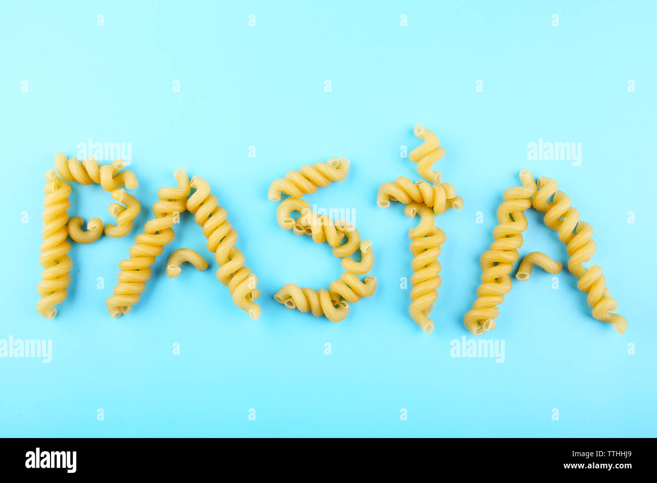 Pasta word made of cellentani on turquoise background Stock Photo - Alamy