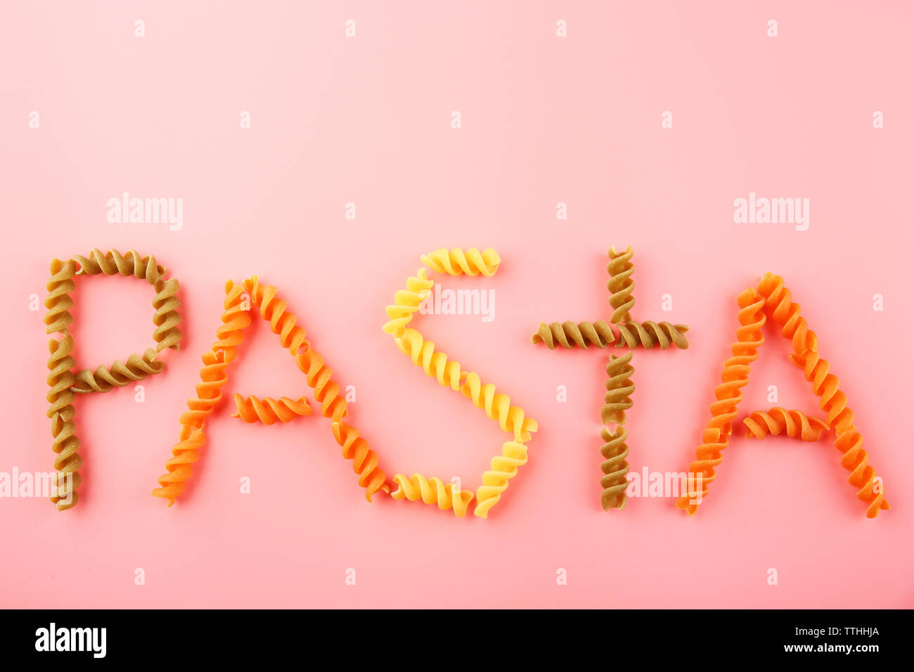 Pasta word made of varicolored fusilli on pink background Stock Photo ...