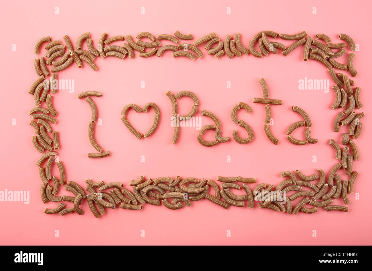 I love pasta inscription made with brown macaroni on pink background ...